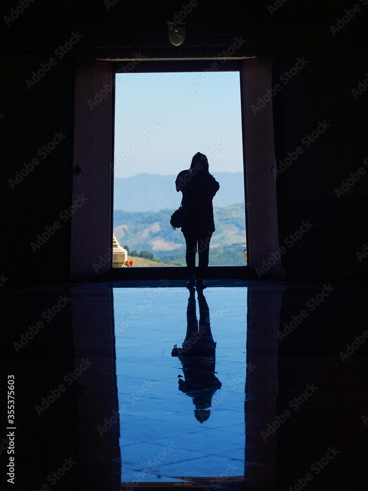 Silhouette a woman standing in the door of buddhist temple with blue ...