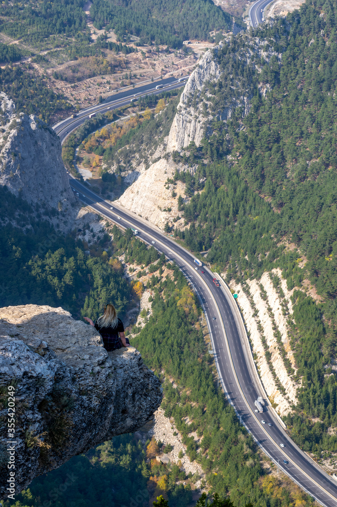 Brave woman is sitting on the rock in front of a chasm. (Gulek Castle ...