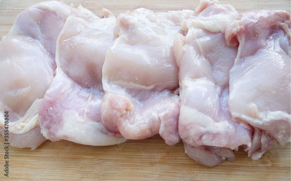Photo Stock Skinless chicken thigh filet on a wooden surface ...