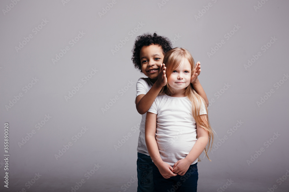 Portrait of two children of different nationalities standing together ...