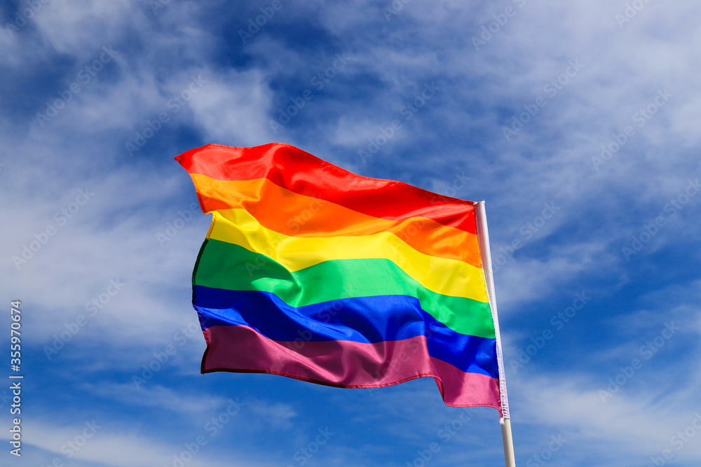 Realistic rainbow flag of an LGBT organization waving in a sky. LGBT ...