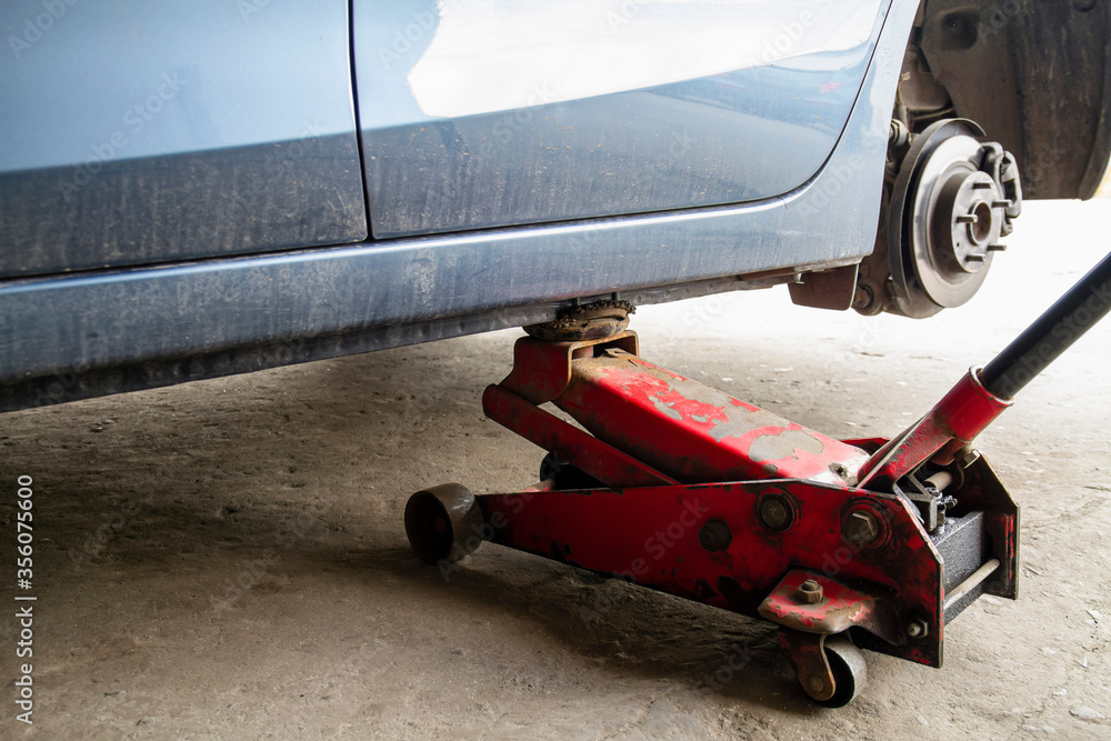 Replacing wheels on a car, jack holds the body in raised position. Car ...
