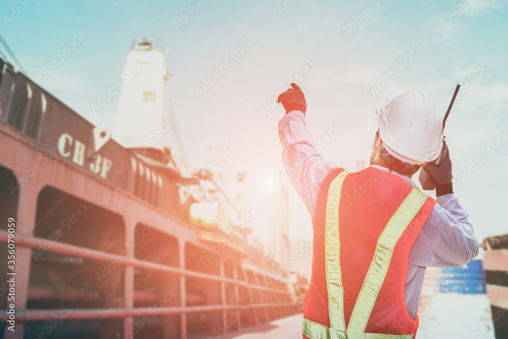 Engineer worker on ship with walkie- talkie in hand holding and operate ...