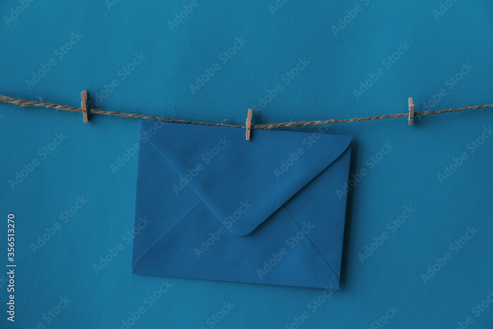 One closed blue envelope hanging on rope isolated blue background ...