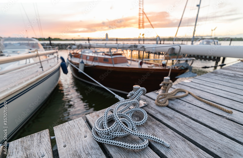 Mooring line with knotted and tied up on wooden pier. Sailing boot tied ...