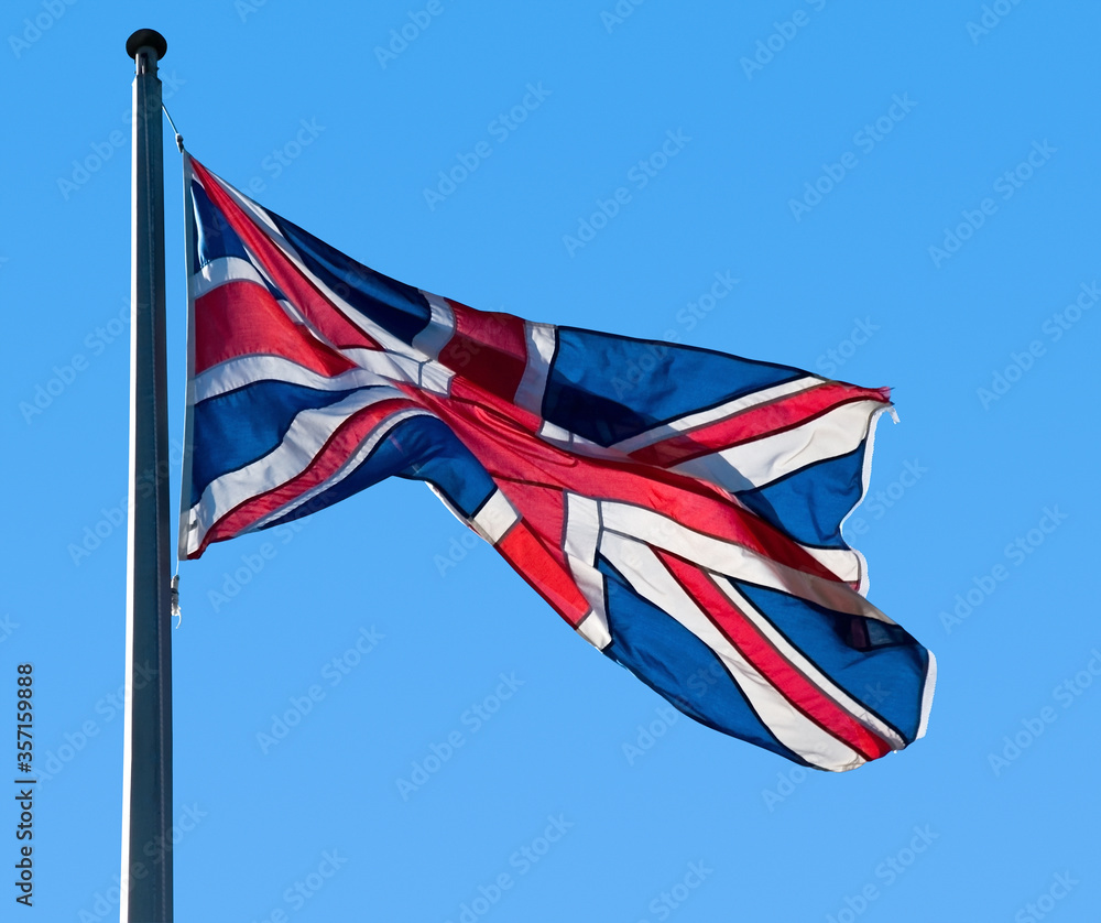 British flag (Union Jack) fluttering in the breeze against a clear blue ...