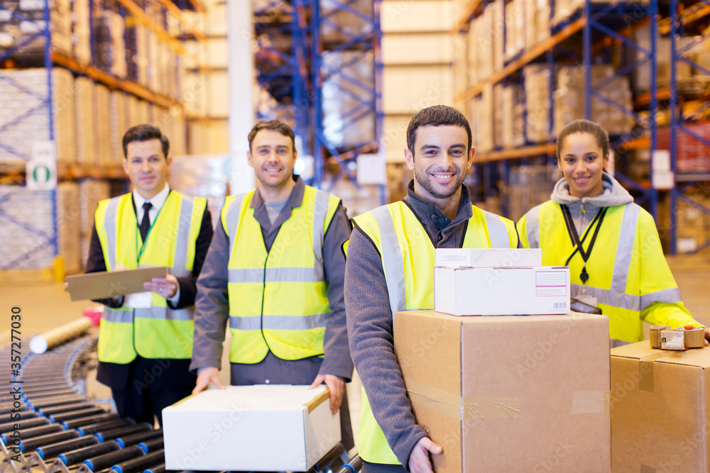 Workers smiling by conveyor belt in warehouse Stock Photo | Adobe Stock
