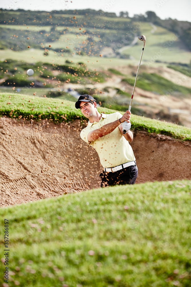 Man swinging from sand trap on golf course Stock Photo | Adobe Stock