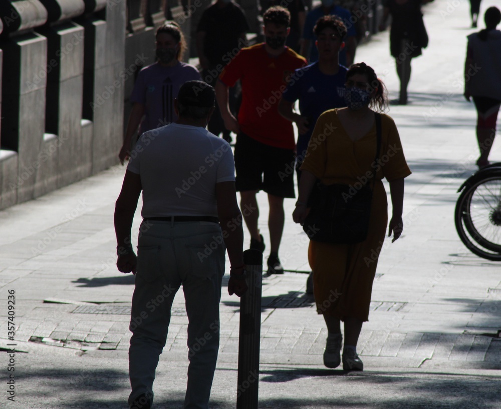Personas a contraluz paseando por una calle Stock Photo | Adobe Stock