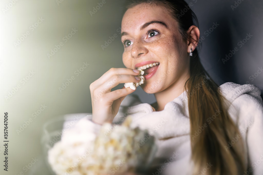 Cute Caucasian woman eating popcorn and laughing while watching Stock ...