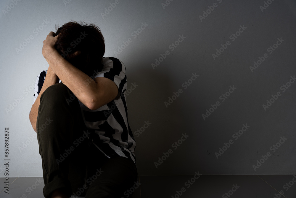 sad man hug her knee and cry sitting alone in a dark room. Depression ...