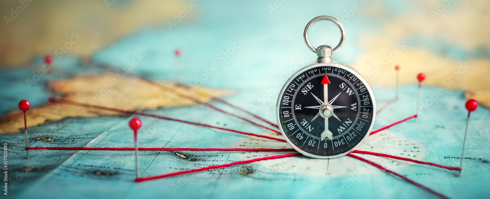 Magnetic compass and location marking with a pin on routes on world map ...