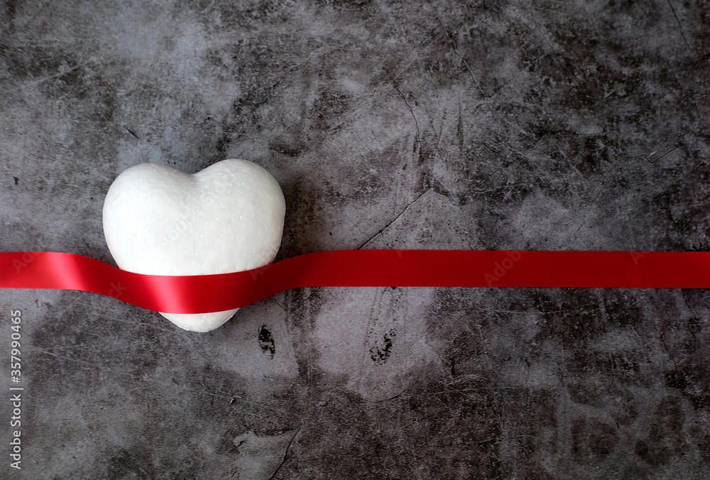 Red ribbon as a symbol of the lack of pulse in the white heart on a ...