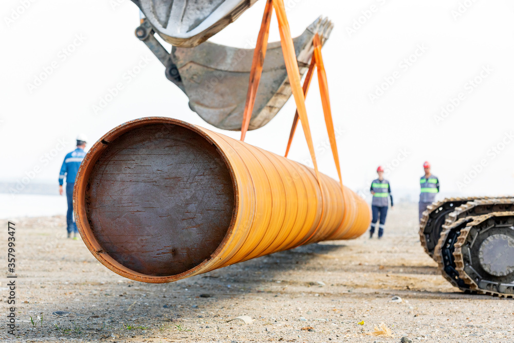 Excavators are lifting a large steel pipe pile and occupational safety ...