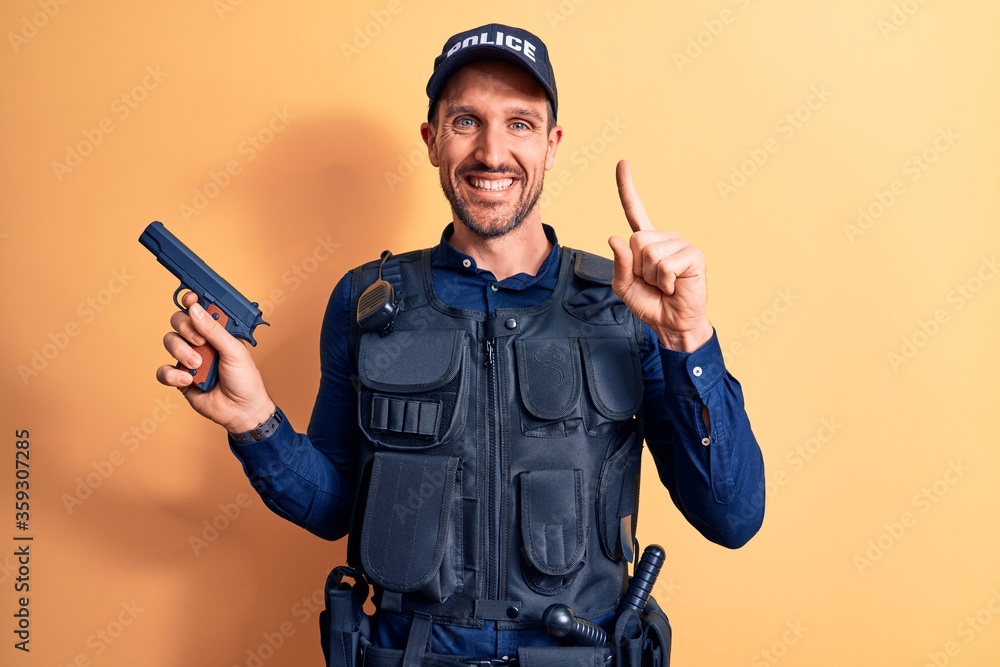 Handsome policeman wearing uniform and bulletprof holding gun over ...