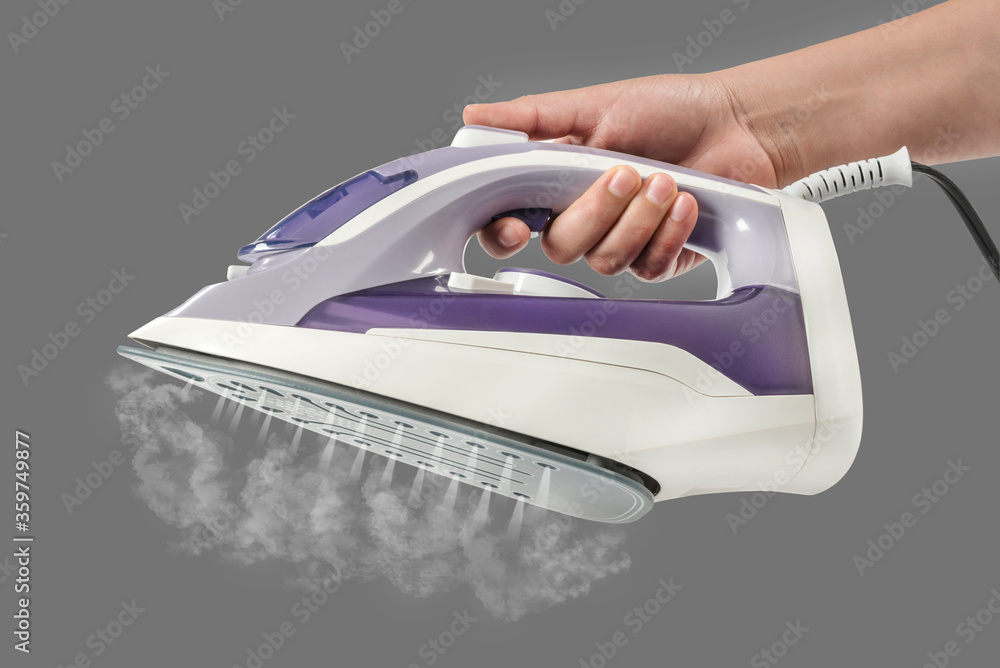 Steaming iron in hand Holding a modern iron expelling hot steam through ...