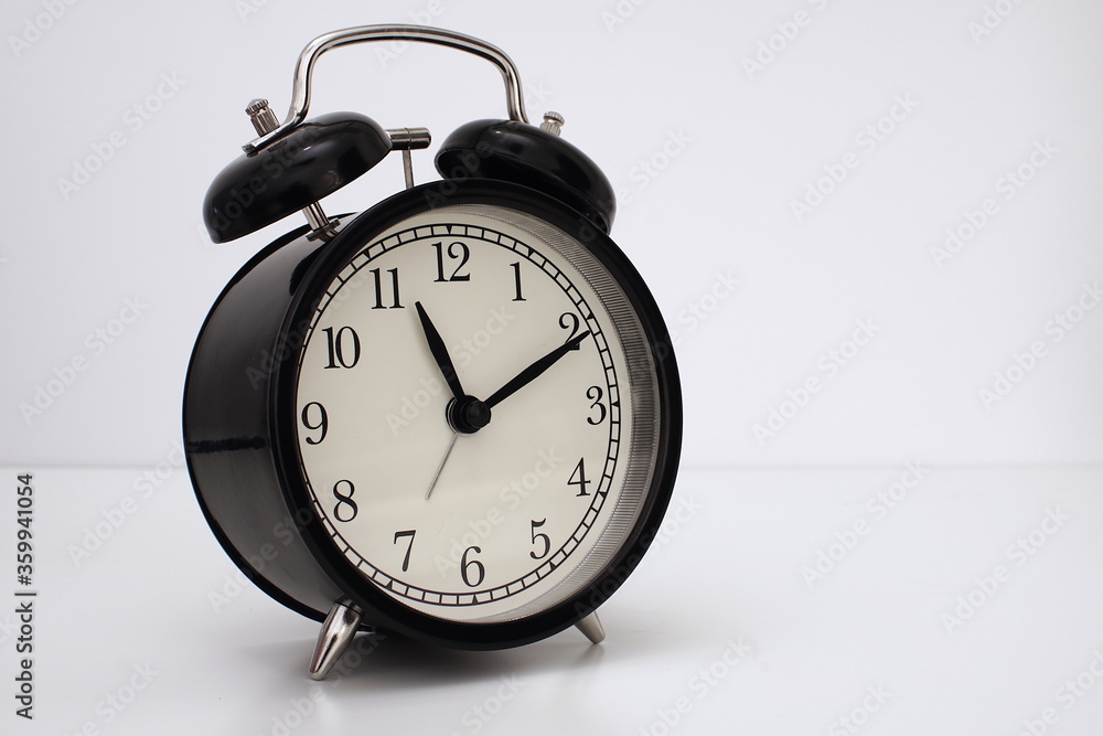 Black vintage alarm clock on table. White background. Wake up concept ...