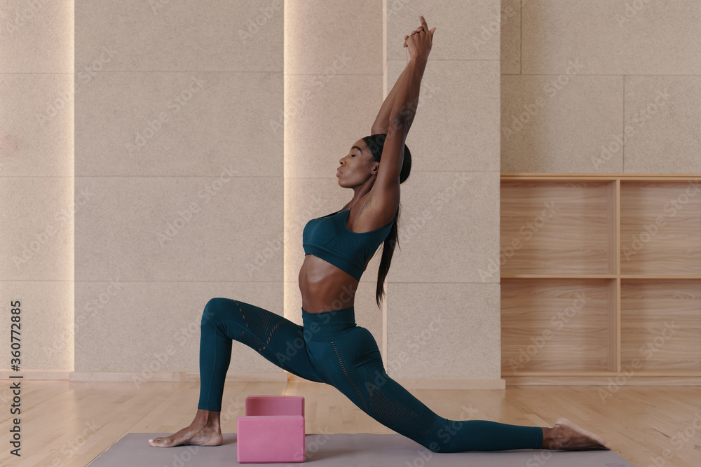 Young black woman practicing yoga, doing Virabhadrasana 1 exercise ...