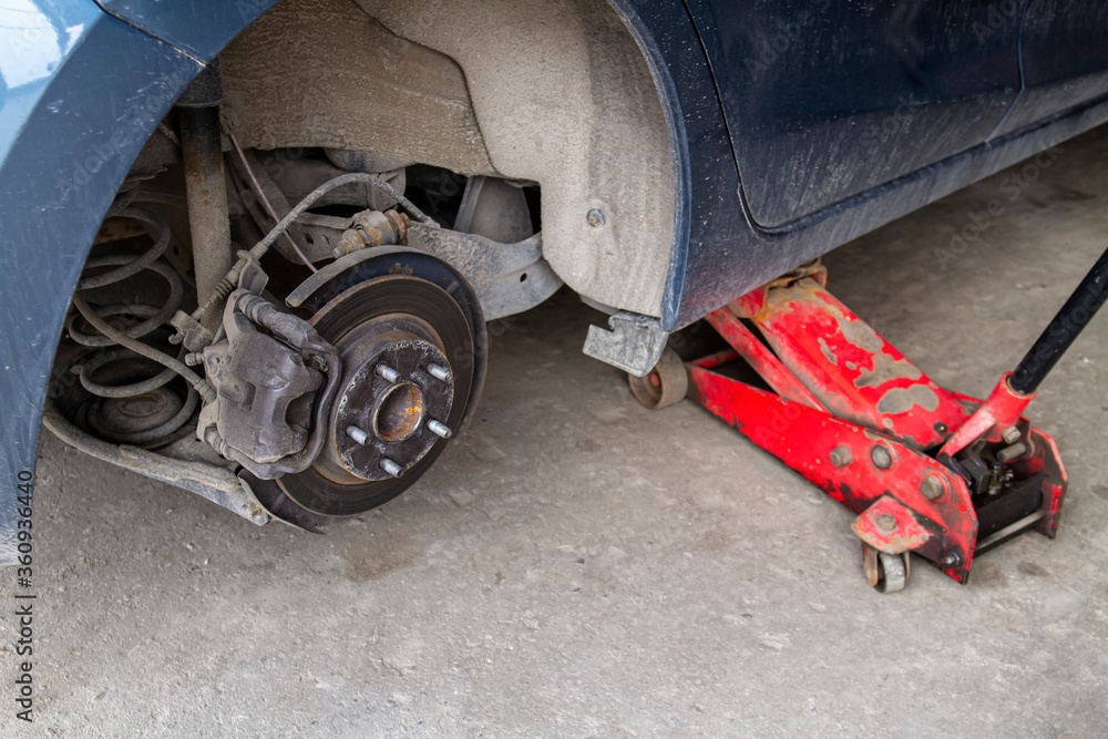 Replacing wheels on a car, jack holds the body in raised position. Car ...