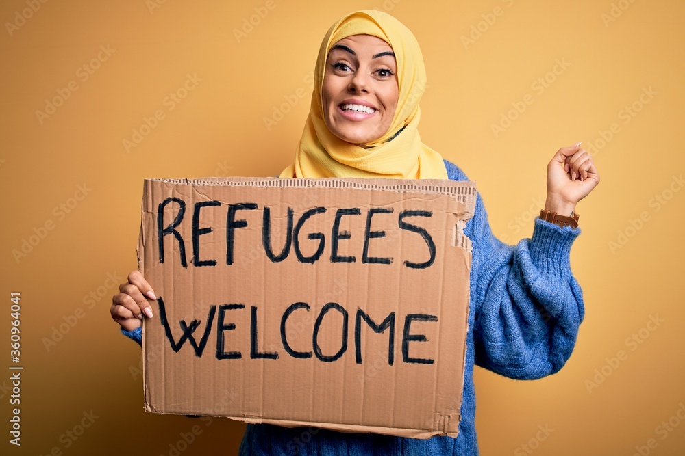 Beautiful arab woman wearing islamic hijab holding banner with refugees ...
