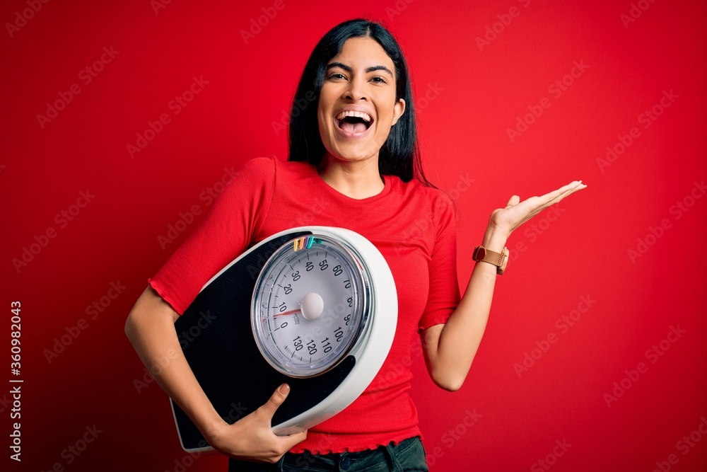 Photo Stock Young beautiful hispanic fitness woman holding scale for ...