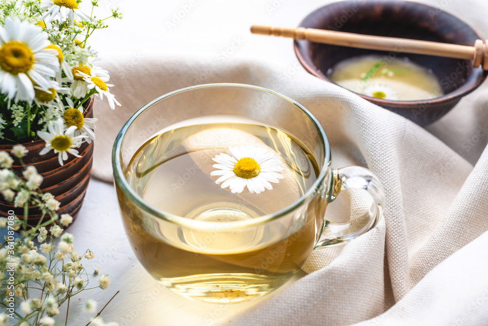Transparent cup of hot chamomile tea and honey. Concept of a healthy soothing herbal drink after ...