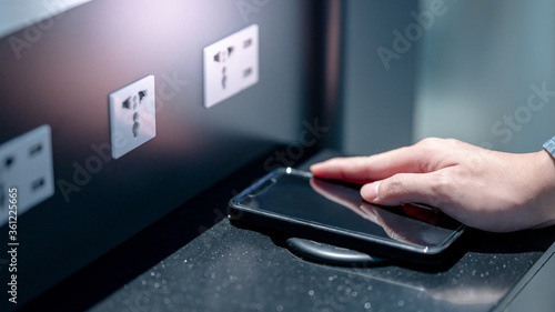Male hand putting smartphone on wireless charger or induction charger ...