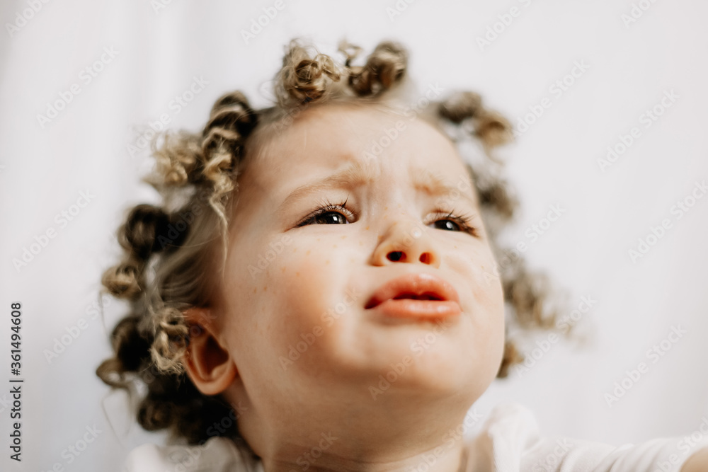Fotografie Little curly girl is crying very emotionally, face with ...