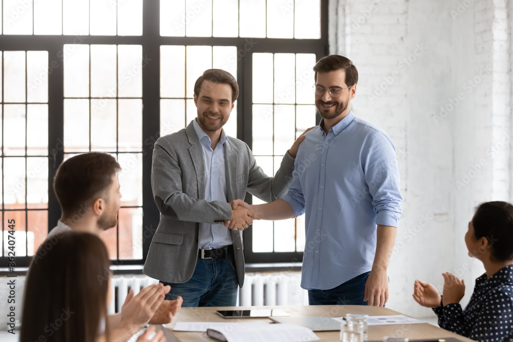 Boss shake hands introduces new employee to members during briefing in ...