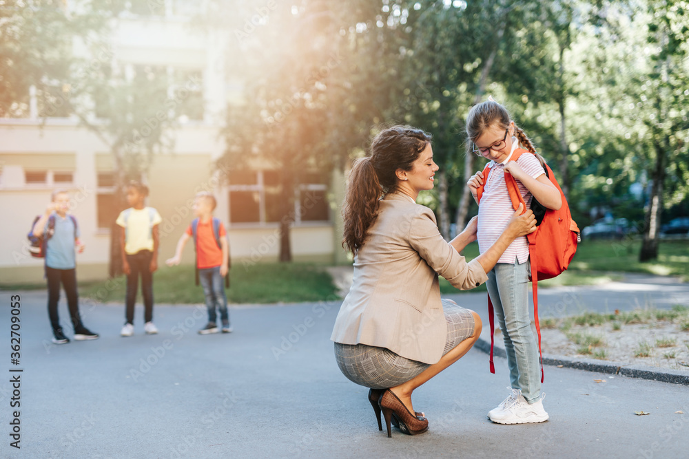 First day at school. Mother leads a little child school girl in first ...