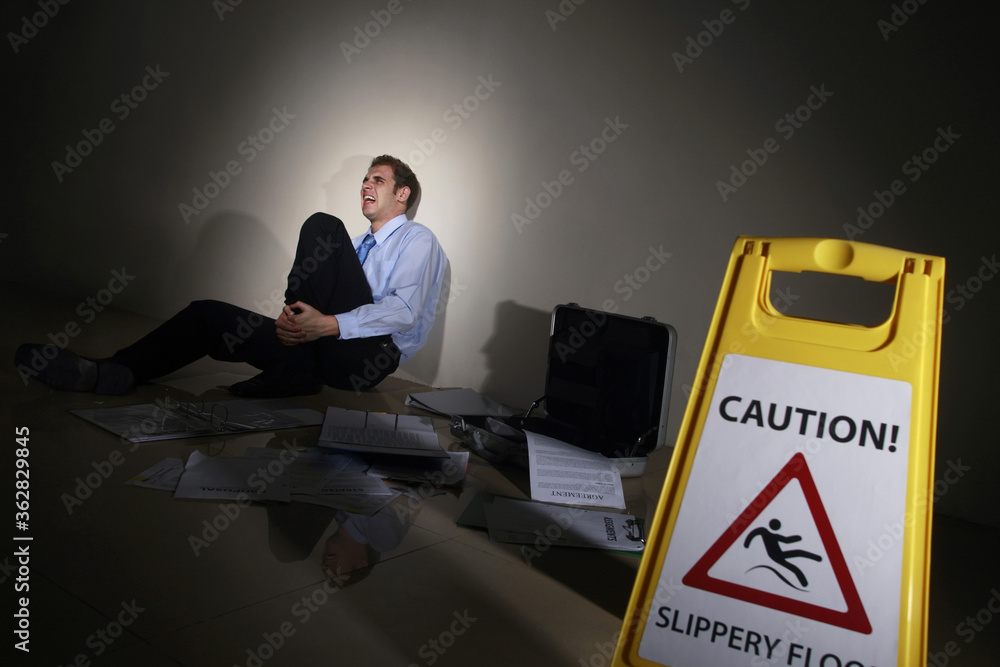 Businessman slipped beside Caution sign, holding onto his leg Stock ...