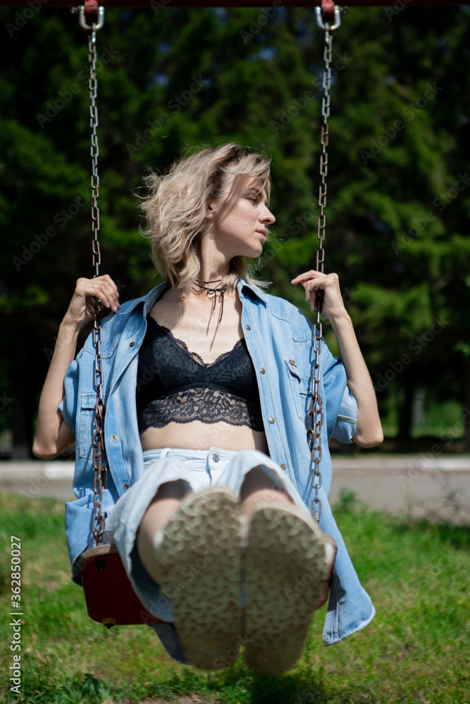 A Woman Swings On A Swing Stretching Her Legs A Blonde Girl In A Denim