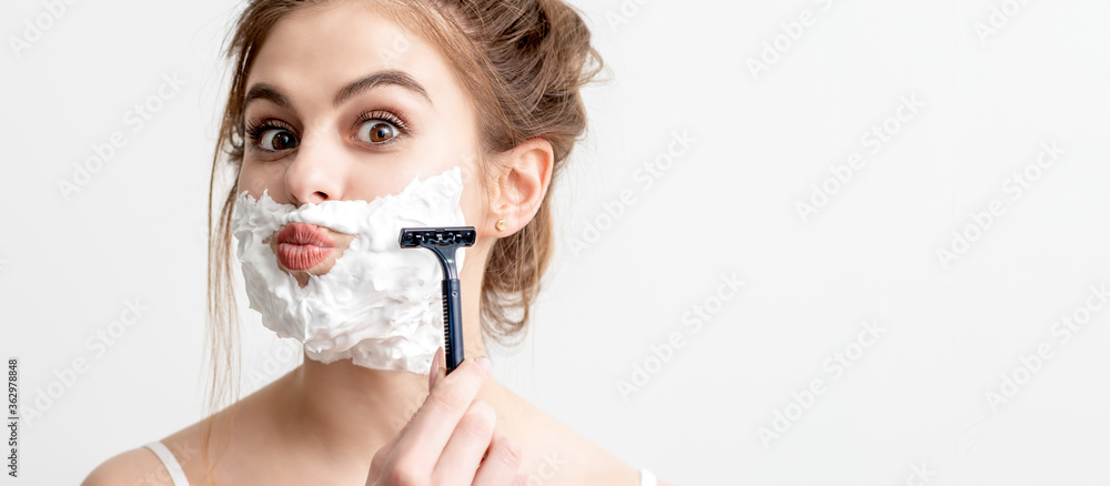 Beautiful young caucasian woman shaving her face by razor on white ...