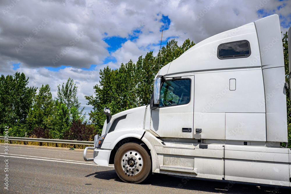 Profile of dirty after the rain white big rig semi truck tractor with ...