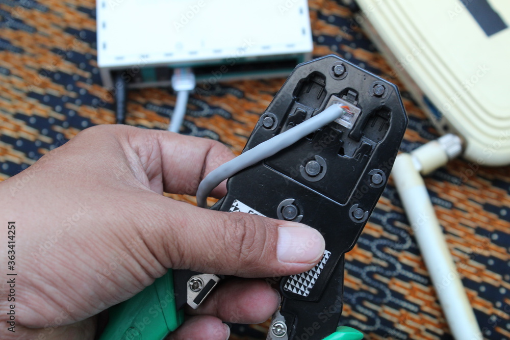 Selective focus to RJ45 Connector with crimping RJ45 tool on blurry ...