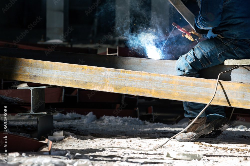 The welder is welding to steel profile with covered electrode in the ...