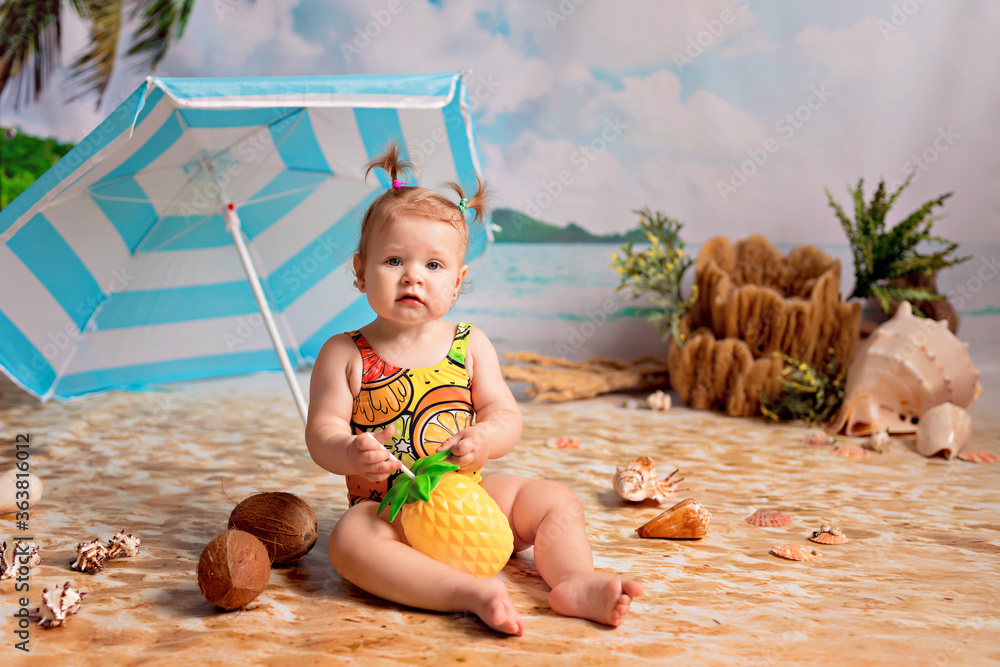 Happy little girl in a pink bathing suit, 12 months old baby, sitting ...