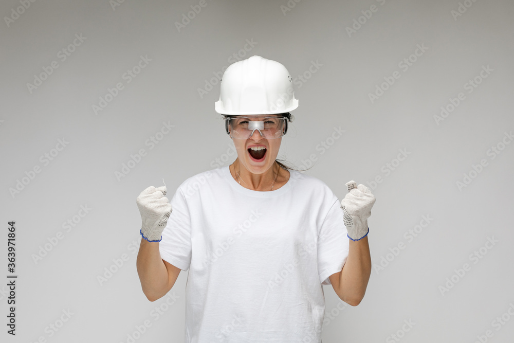 contented girl architect in a construction helmet on a light background ...