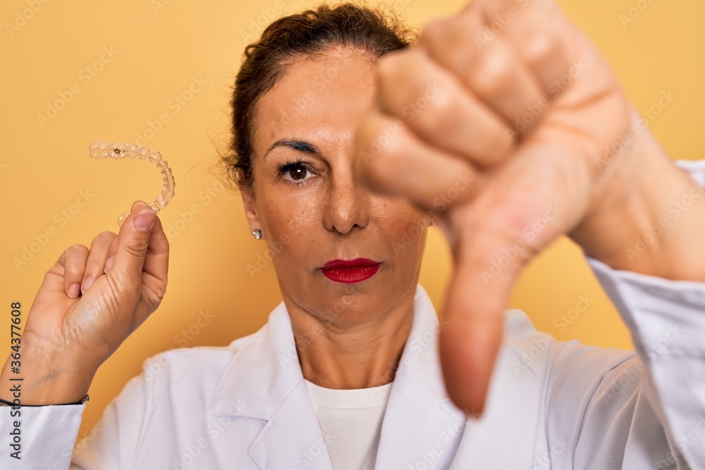 Middle age senior dentist woman holding clear aligner for teeth ...