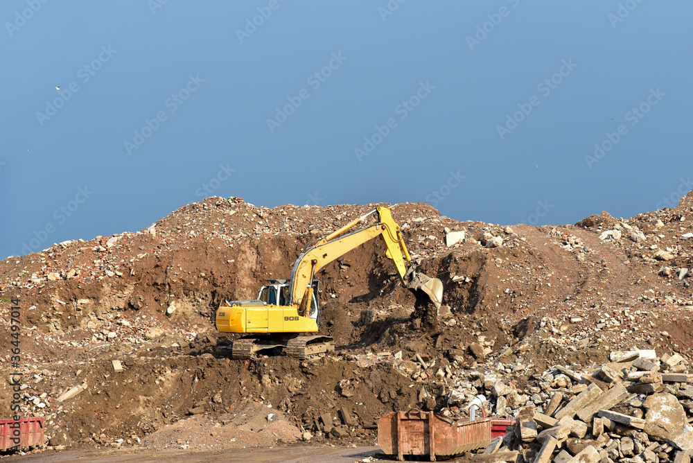Excavator at landfill for the disposal of construction waste. Backhoe ...