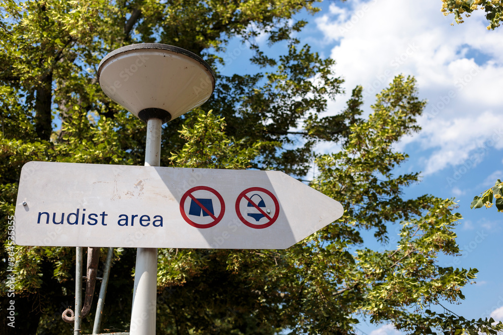 Information sign indicating designated area for nude sunbathing. Nudist ...