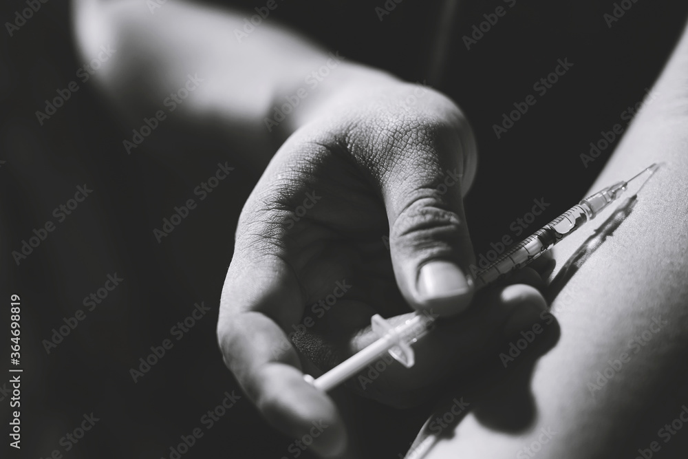 close up photo monochrome man hand of a drug addict and a syringe with ...