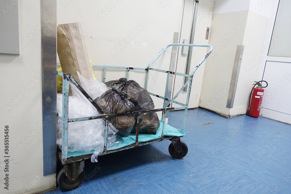Old metal cart with black garbage bags in poor hospital hole. Dirty ...