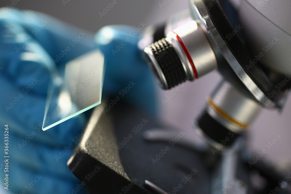 Professional researcher wearing rubber gloves while doing chemical research and using lenses of ...