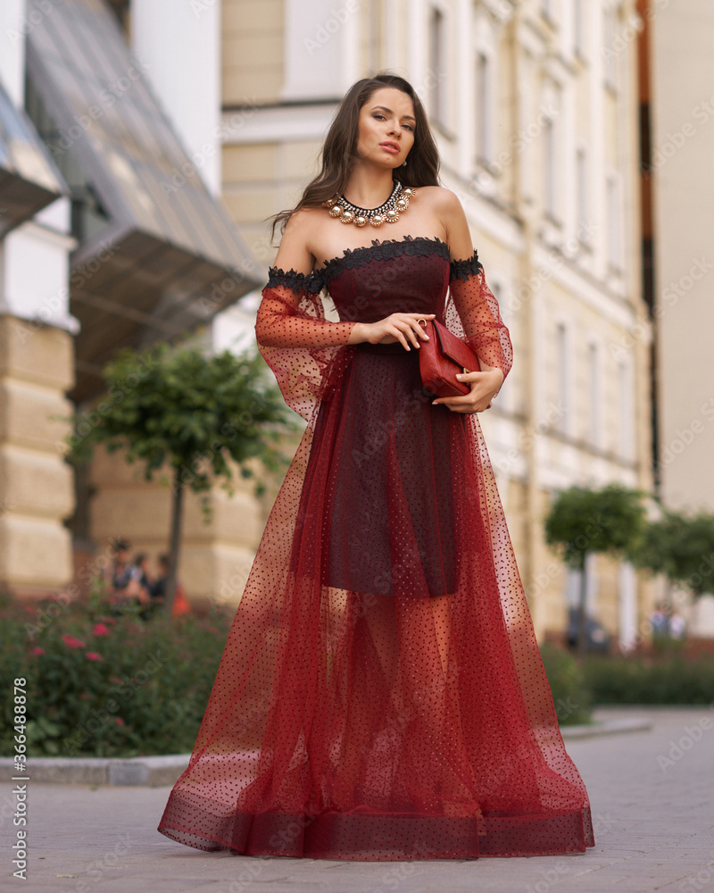 Elegant fashionable female model in red long evening dress with open ...