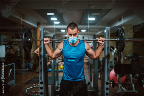 A young caucasian athlete man with a mask on his face exercises and ...