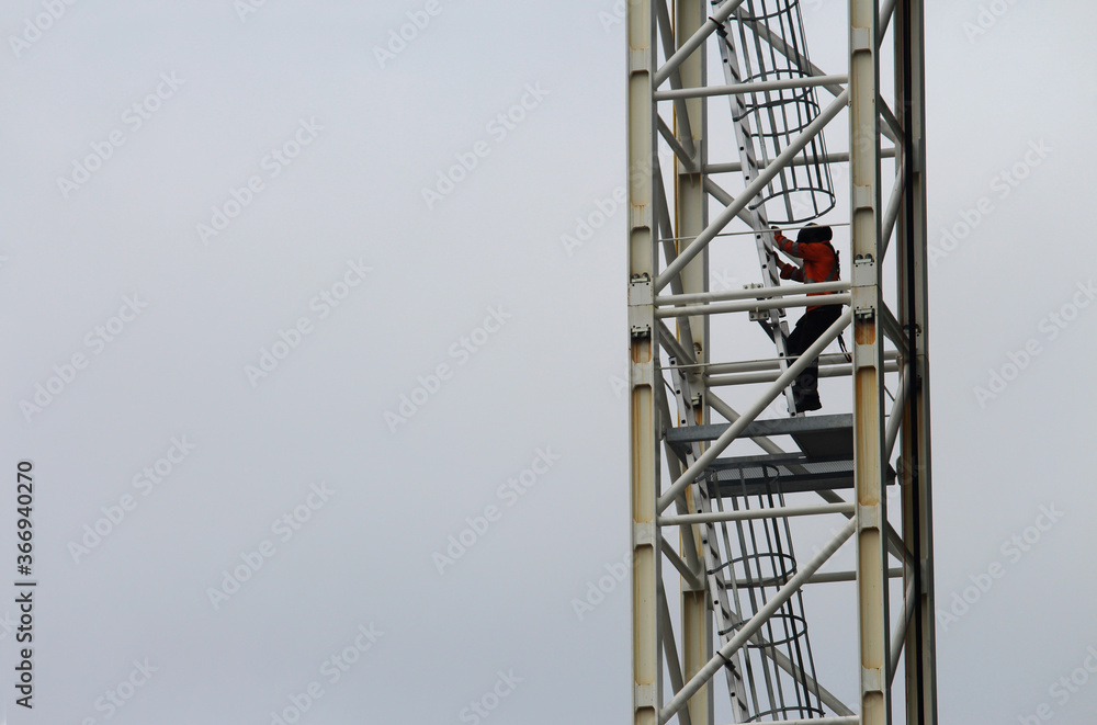 Workman climbing down the ladder in the shaft of a crane on an ...