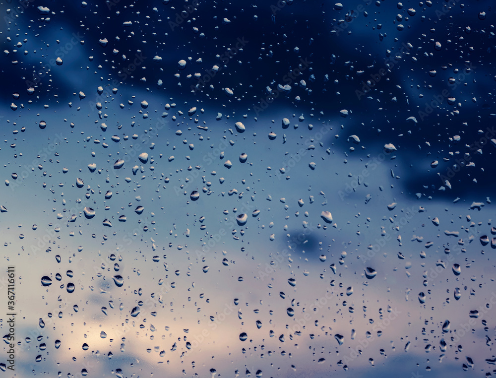 blue rain water drops on a window glass close up with deep dark storm ...