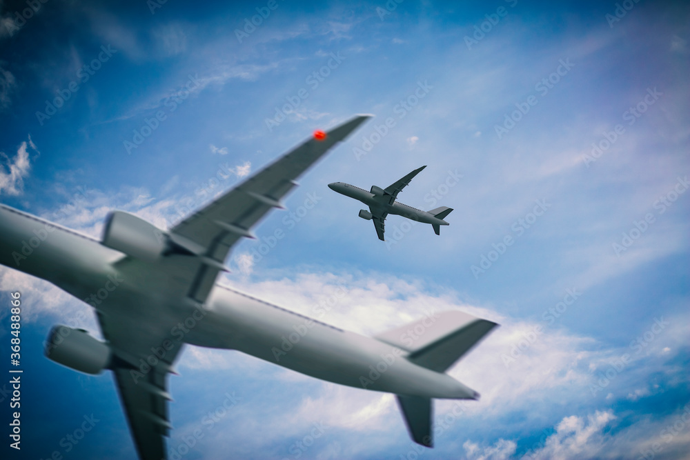 Two air planes flying parallel in the sky with the near one off focus ...