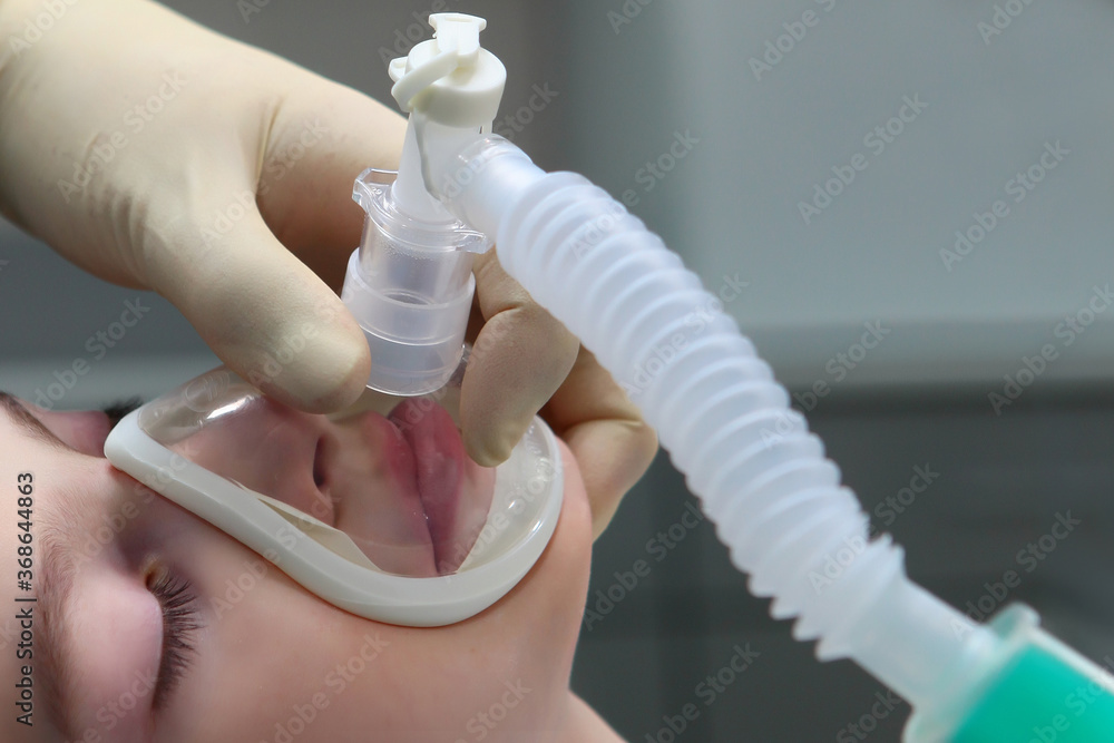 Administration of anesthesia before surgery to a young boy. Breathing ...